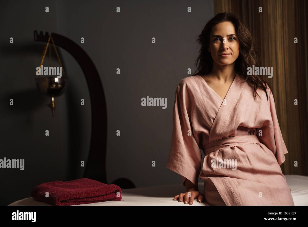 Brunette white woman wearing robe sitting on couch in spa indoors Stock ...