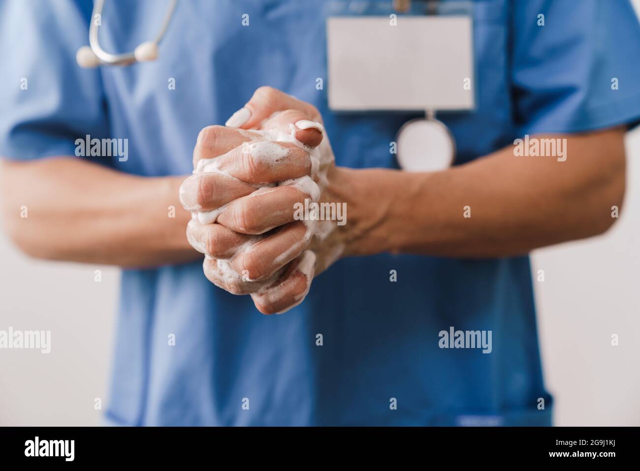 Close up of a female doctor washing her hands with soap isolated over ...