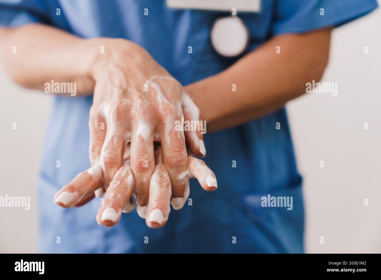 Close up of a female doctor washing her hands with soap isolated over ...