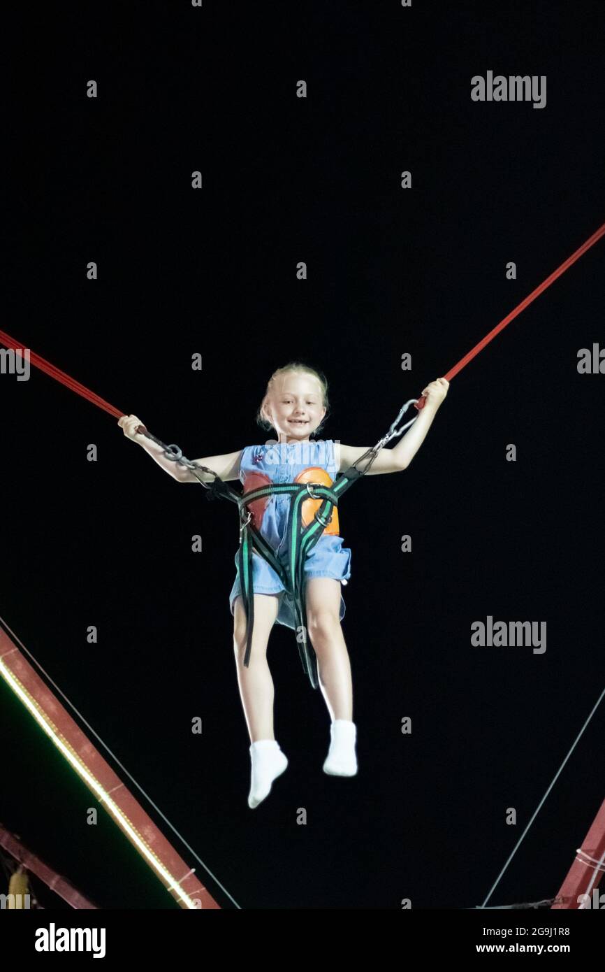 Little girl with blond hair in the air on the catapult ride against the ...