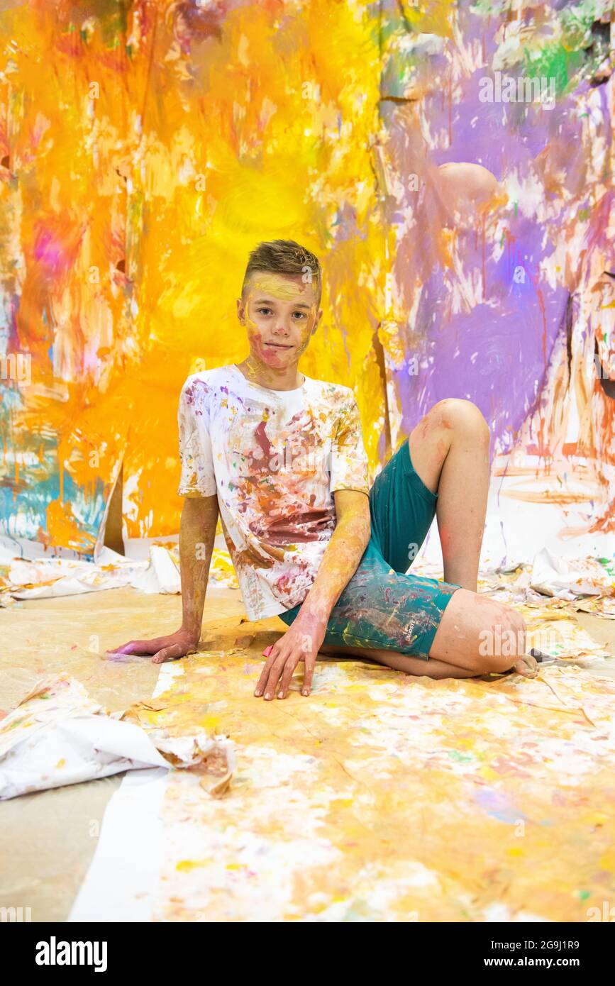 Portrait of a cute happy boy painting and having fun. He is showing his ...