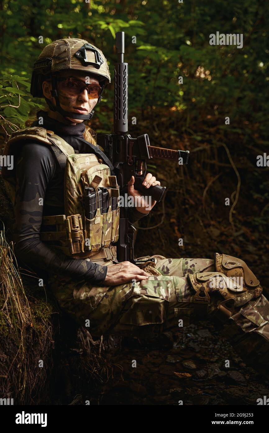 Cute female person in ambush holding gun Stock Photo - Alamy