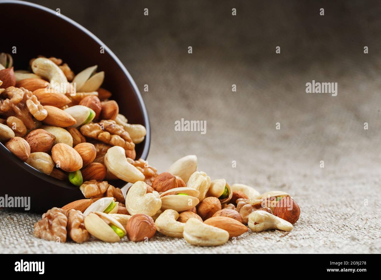 Assorted nuts in a plate on a wooden table with a burlap cloth ...