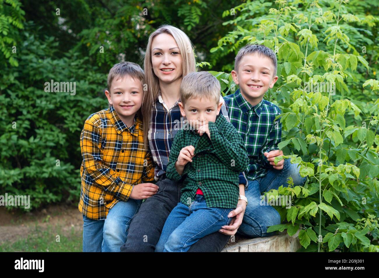 Single parent family with three children sitting on tree stumpand ...