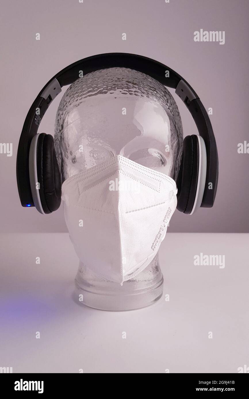 Glass model head with headphones and Covid-19 protective face mask ...