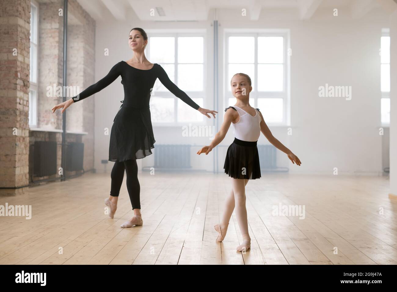 Little girl in tutu dress learning to dance the ballet together with ...