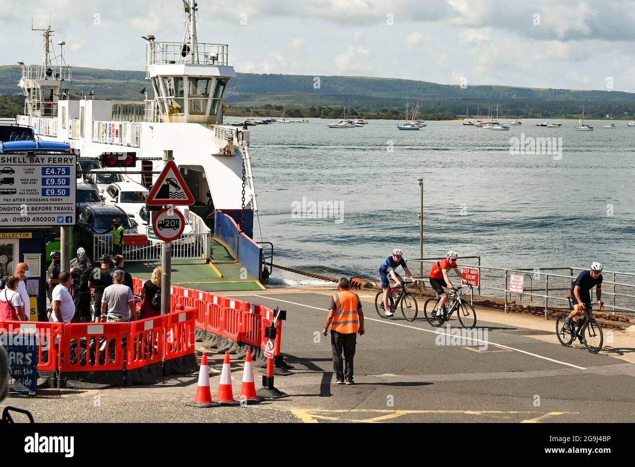 Poole, Dorset, England - June 2021: Cyclists riding off the chain ferry ...