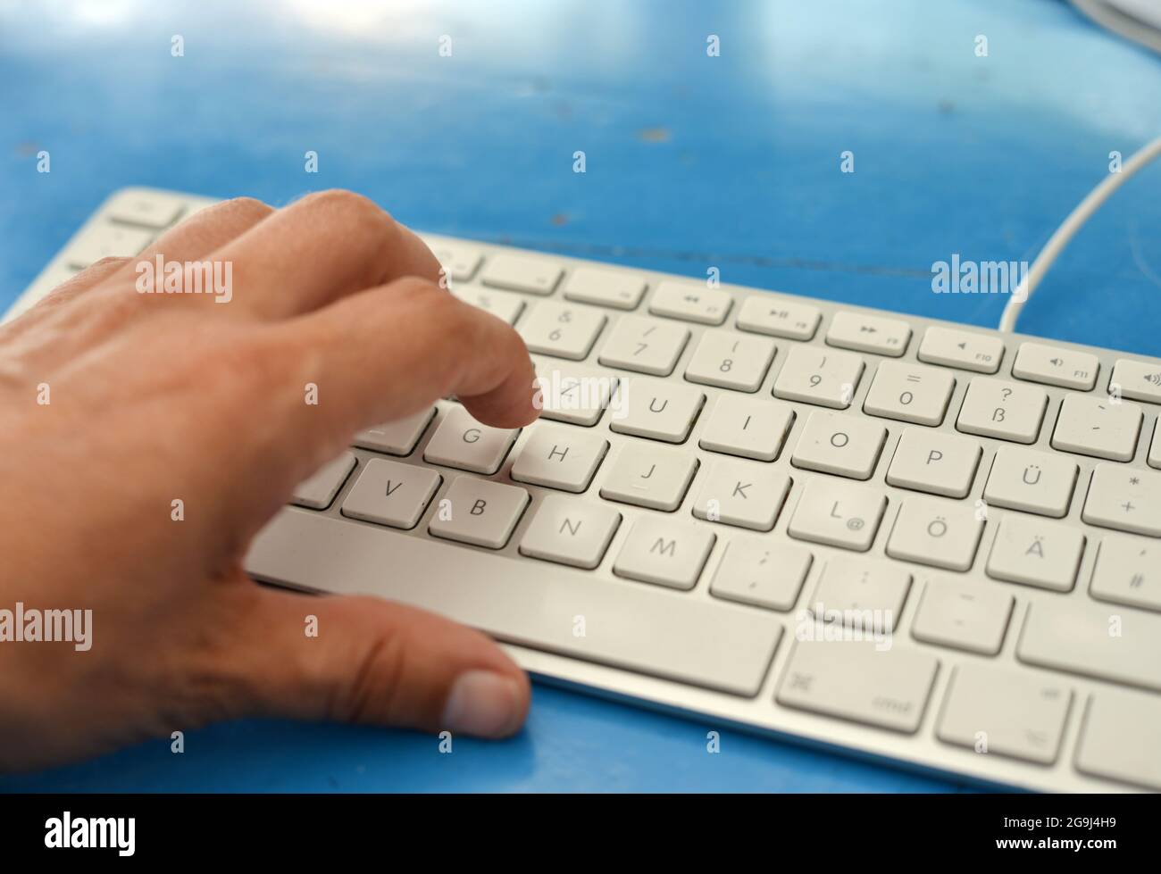 Hand typing on a computer keyboard laying on a blue desk Stock Photo ...