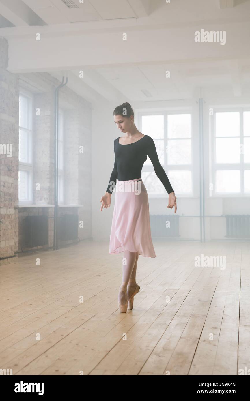 Portrait of beautiful ballet dancer stretching her leg during ballet ...