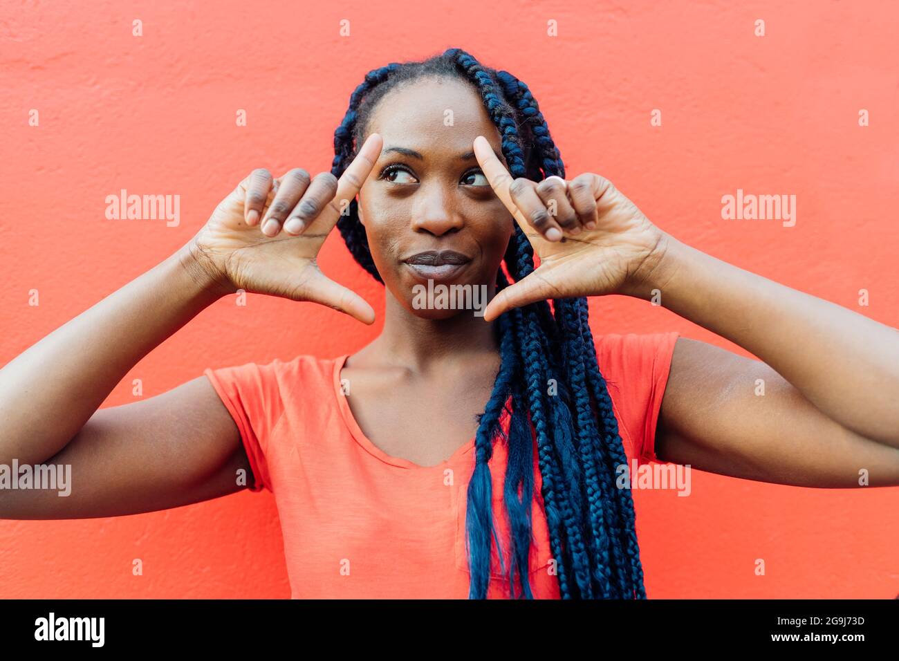 Italy, Milan, Young woman with braids making finger frame Stock Photo ...