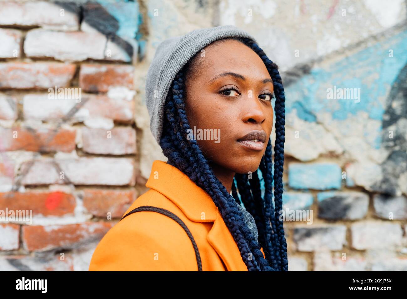 Italy, Milan, Portrait of woman with braids against brick wall Stock ...