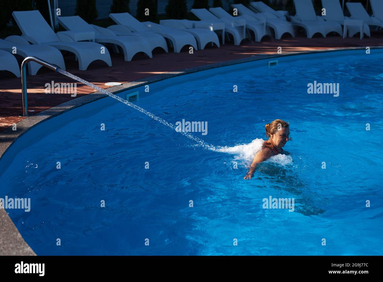 Spa therapy. An elderly woman enjoys a back and neck massage with a jet ...