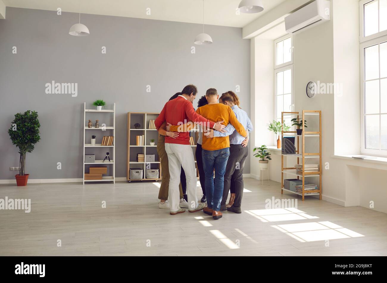Group of people hugging each other standing in a circle in a modern ...