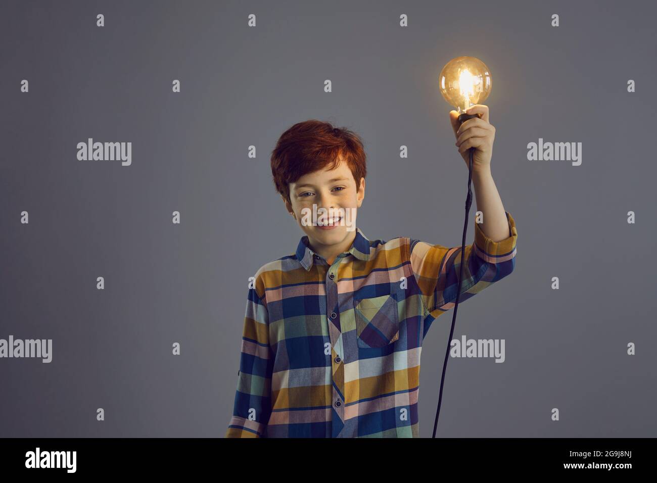 Happy smiling boy child holding glowing lightbulb lamp above head ...