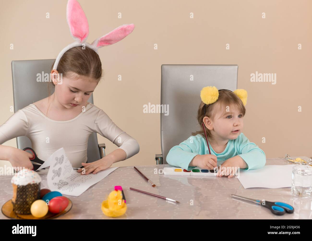 Two sisters at the table draw with paints and cut out paper crafts for ...