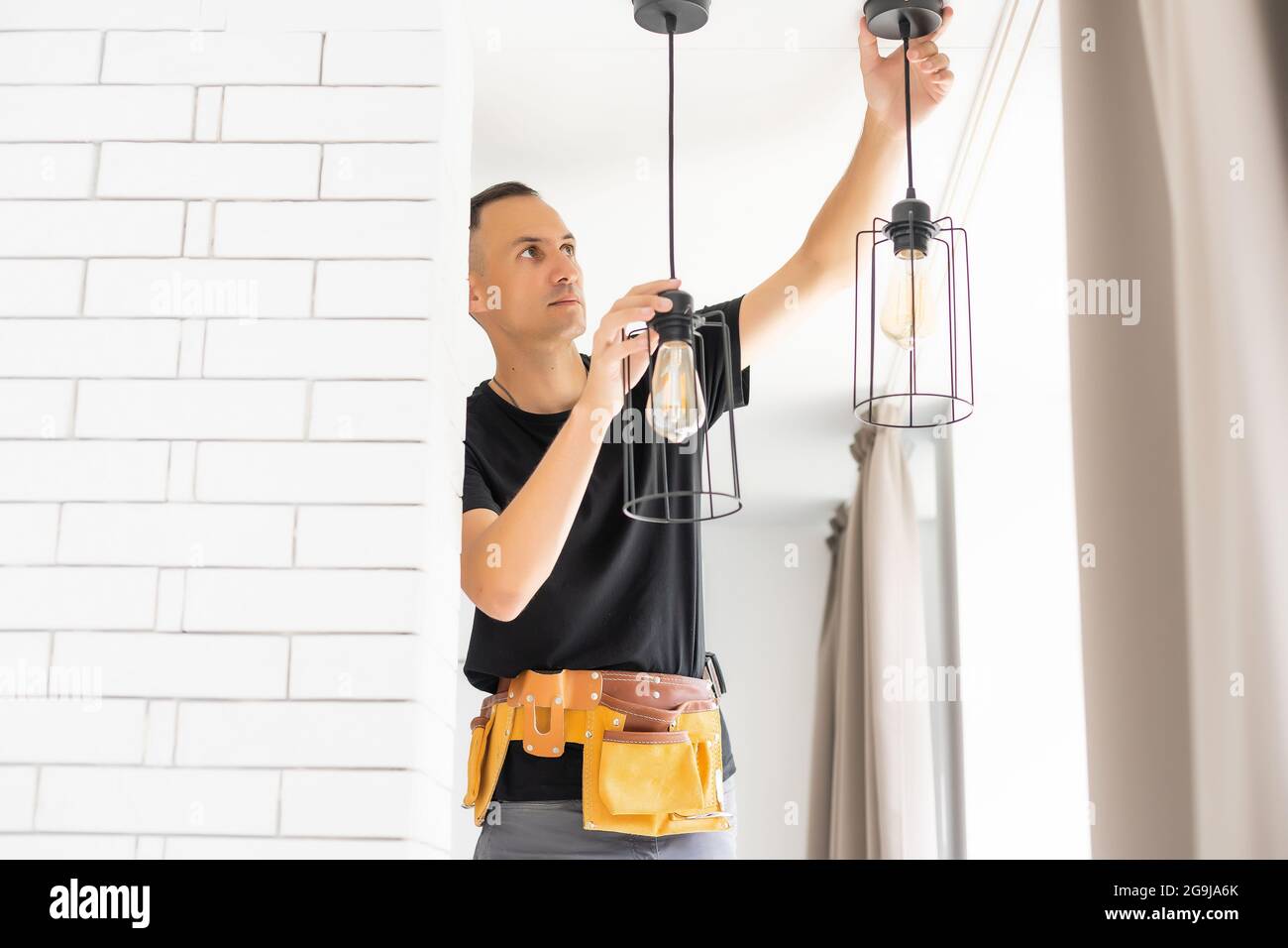 Worker repairing lamp on stretch ceiling indoors Stock Photo - Alamy
