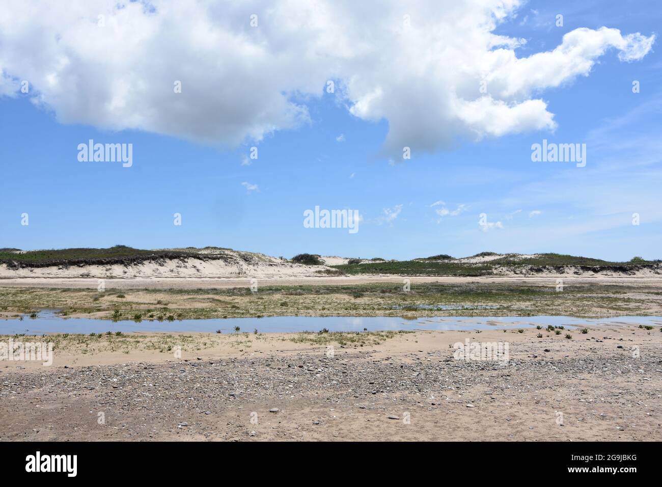 Fluffy clouds and blue skies over sand dunes and marsh Stock Photo - Alamy