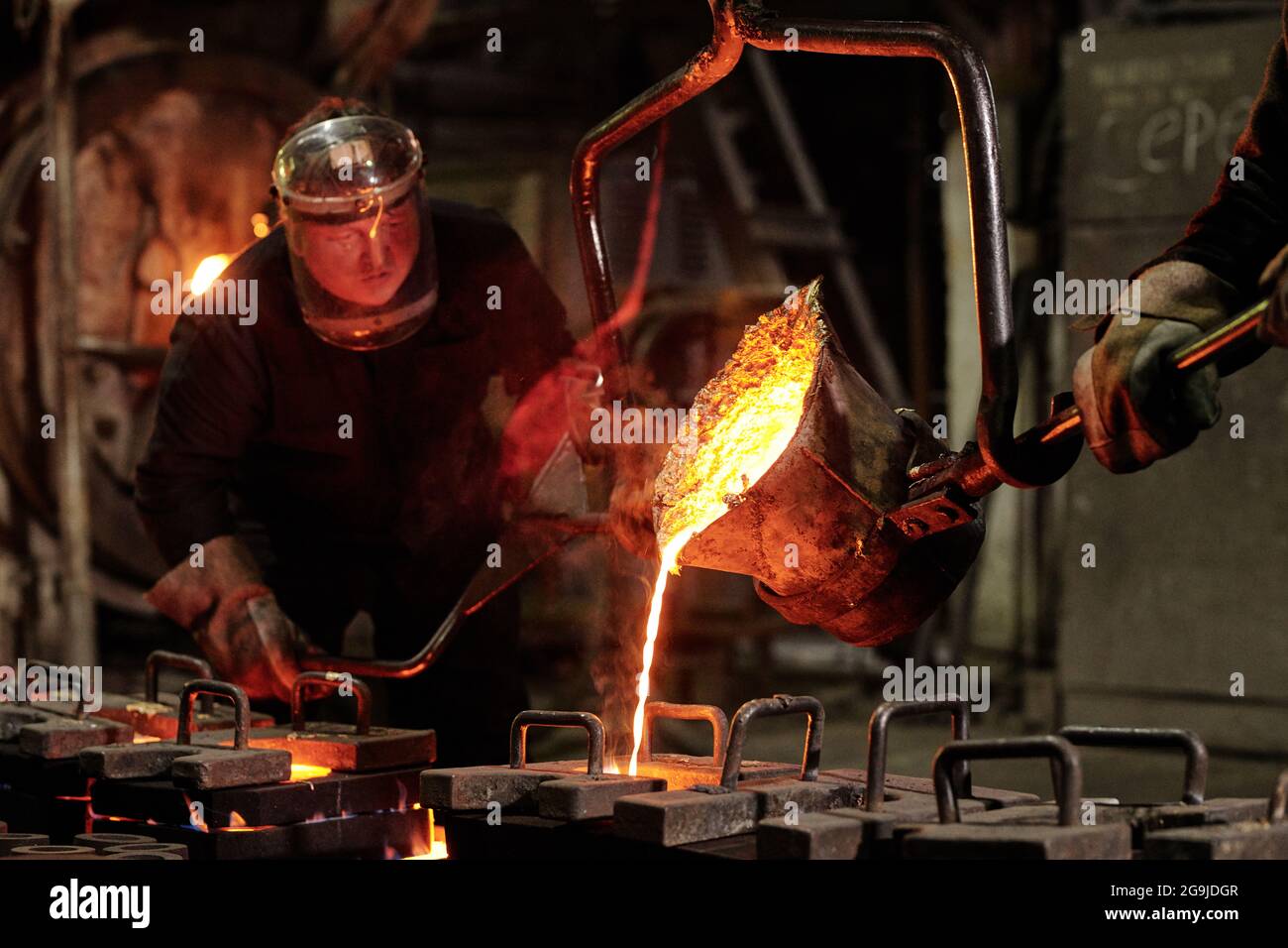 Workers in helmets working in team they melting iron in metal factory ...