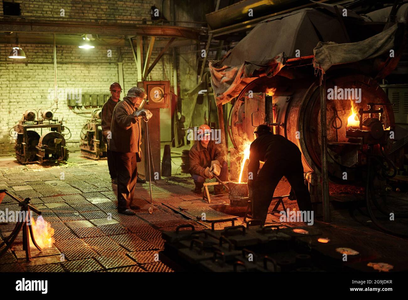 Manual worker melting metal in a furnace for future metal details in ...