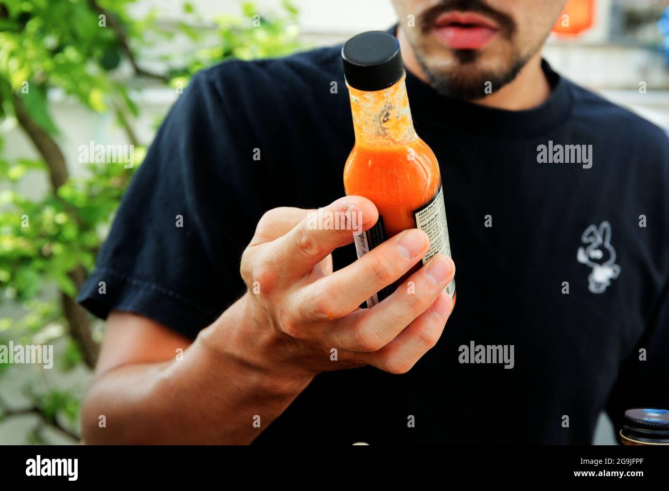 Closeup shot of a male hand holding a sauce bottle and reading the ...