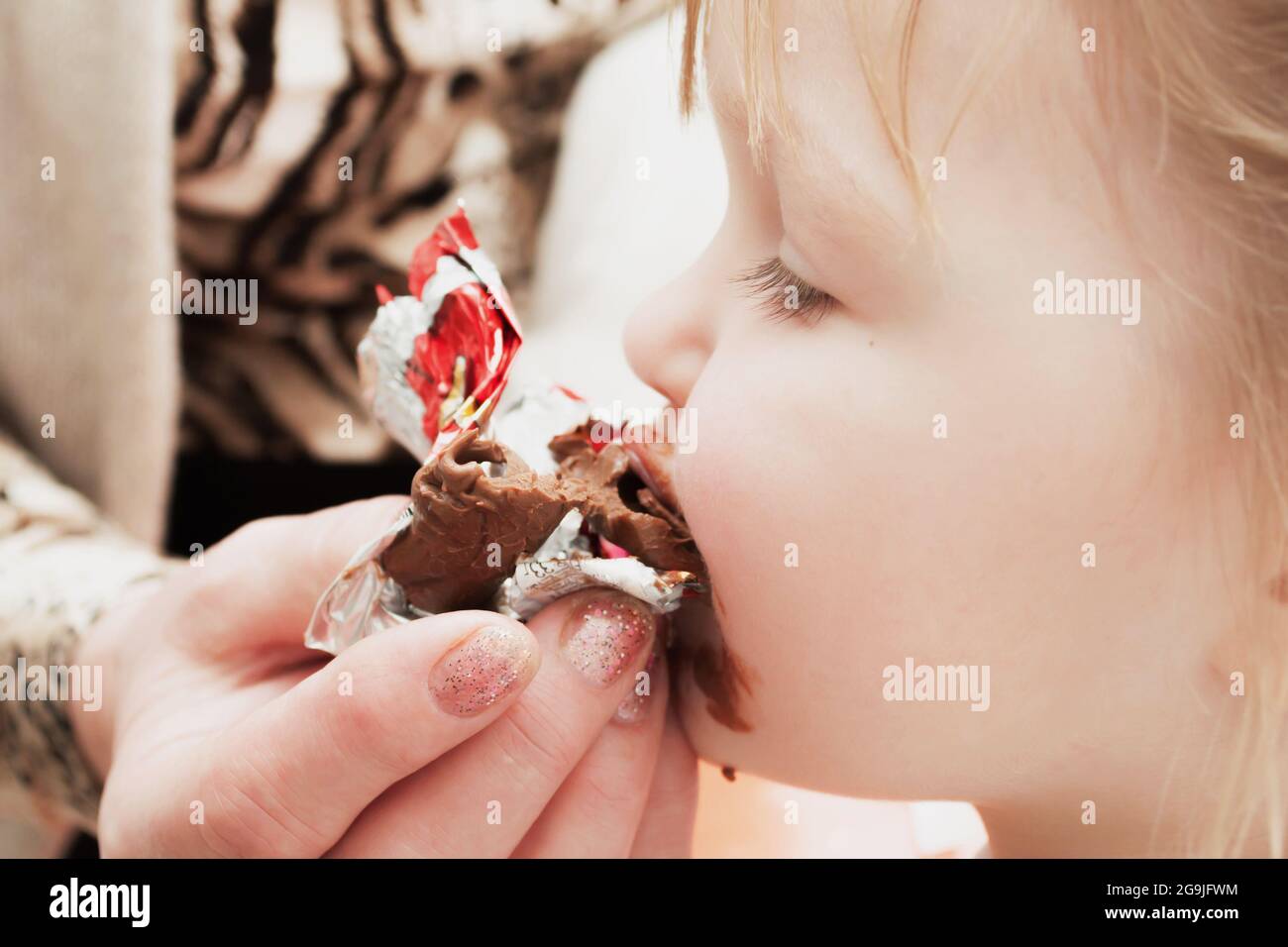 little girl eating chocolate candy. Pleasure Stock Photo - Alamy