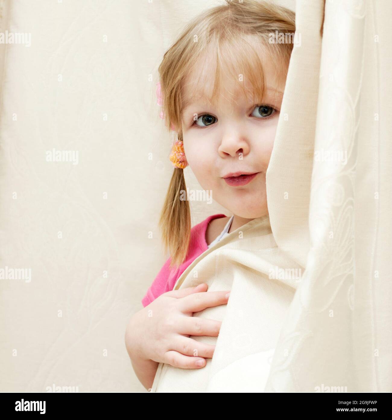 Pretty little girl playing hide and seek Stock Photo - Alamy
