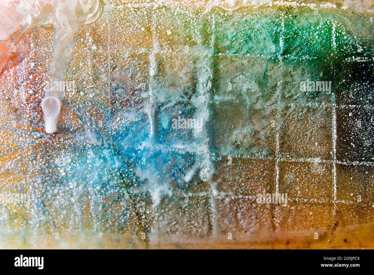 Ice plate melting. Multicolor. Colors trapped inside ice, flowing as ...