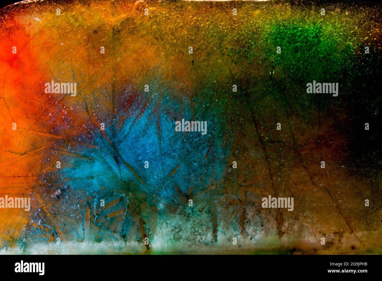 Ice plate melting. Multicolor. Colors trapped inside ice, flowing as ...
