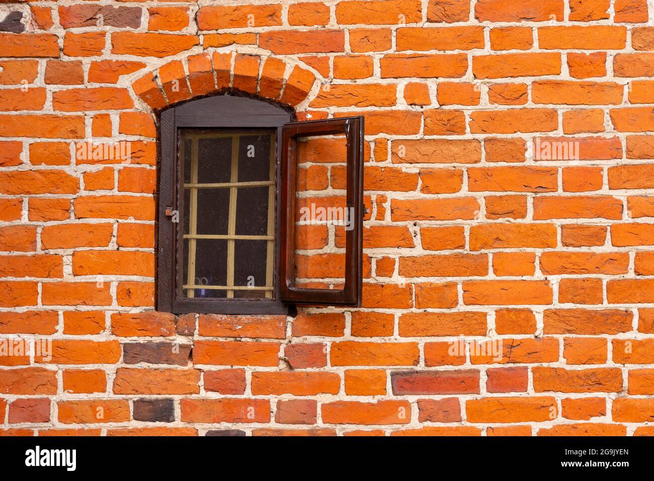A small open window with a window grill on a gothic brick wall.Poland ...