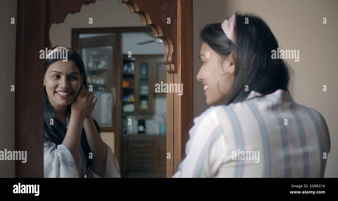 South Asian young female getting ready for a date night as she checks ...