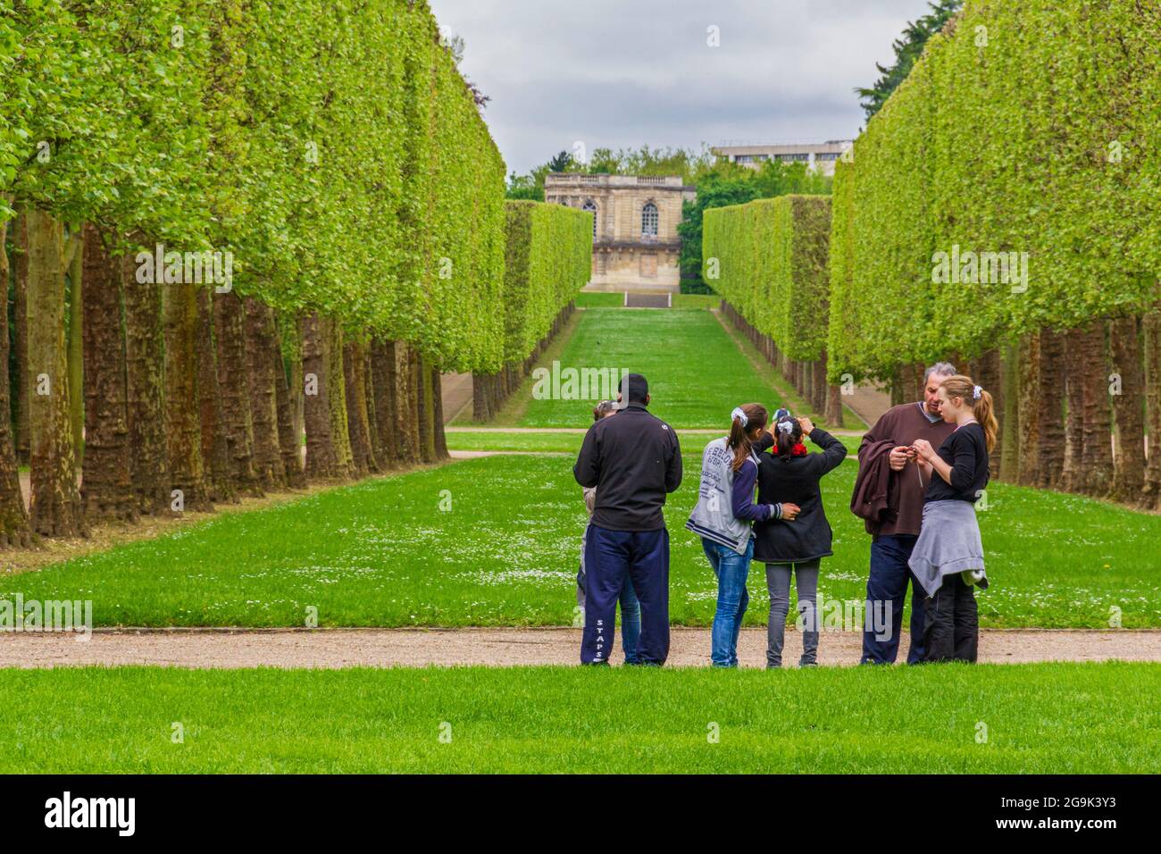 Group of people looking at photos in a formal park with distant chateau ...
