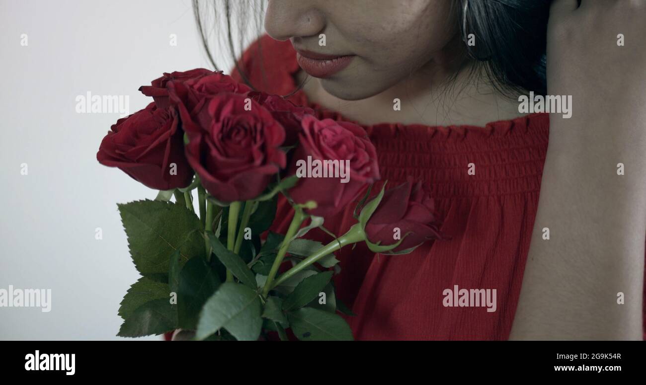 South Asian female smelling the fragrance of red ro Stock Photo - Alamy
