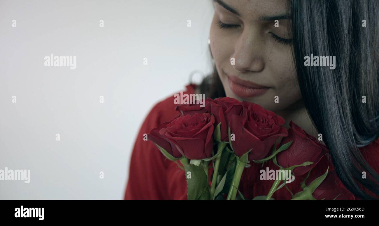 South Asian female smelling the fragrance of red roses Stock Photo - Alamy