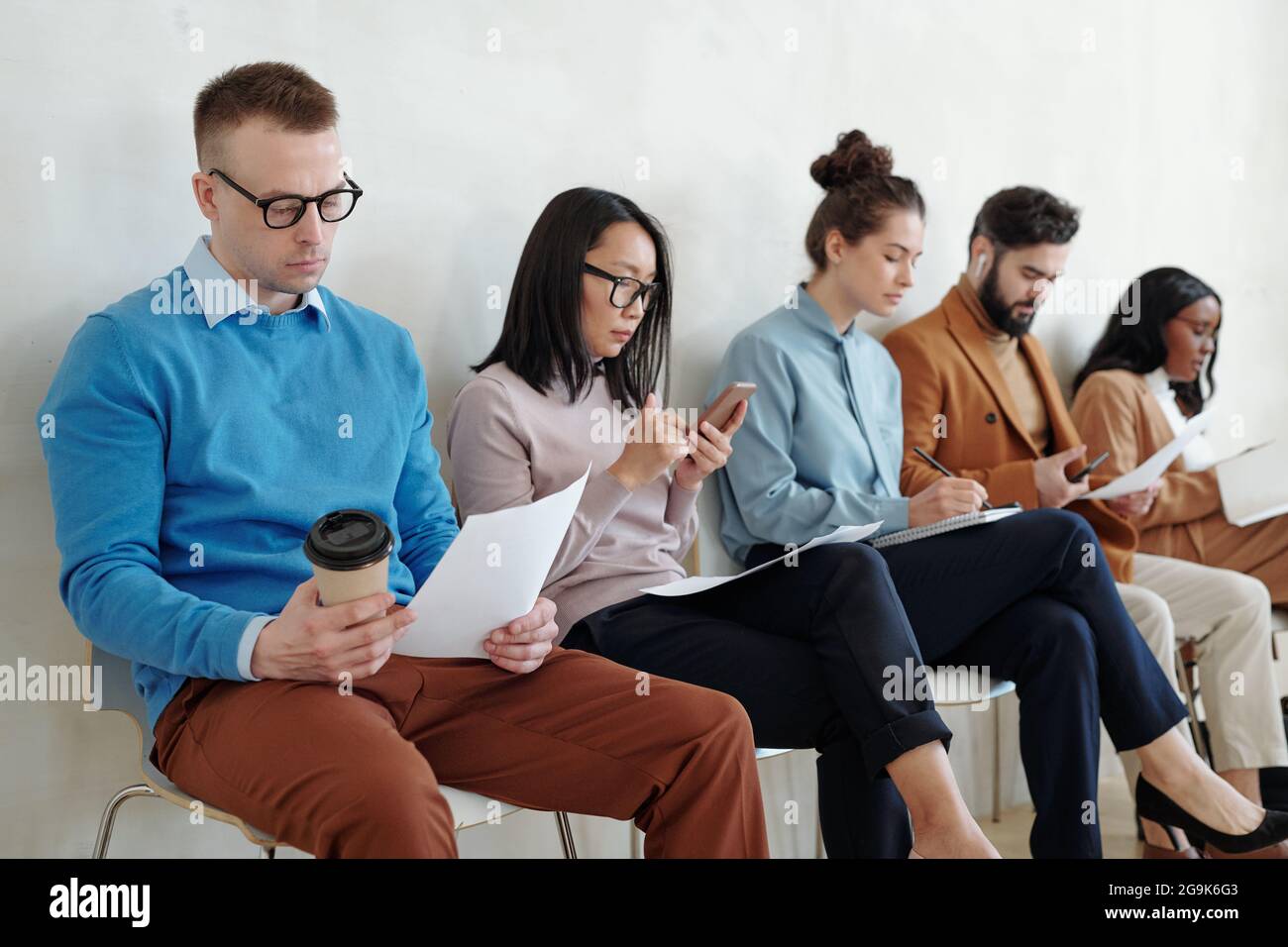 Several young applicants sitting along wall while waiting for their ...