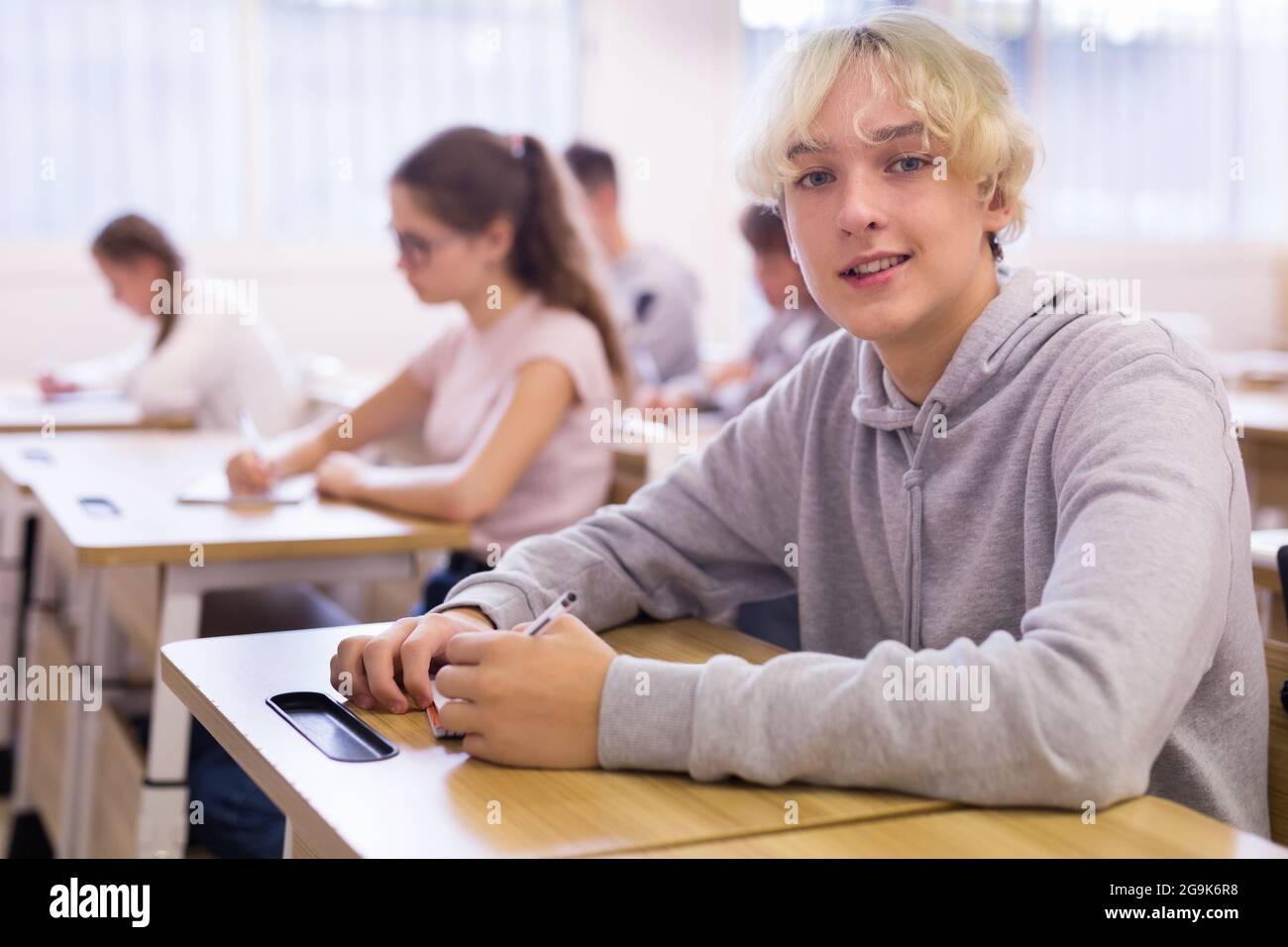 Teen boy sitting at desk in classroom Stock Photo - Alamy