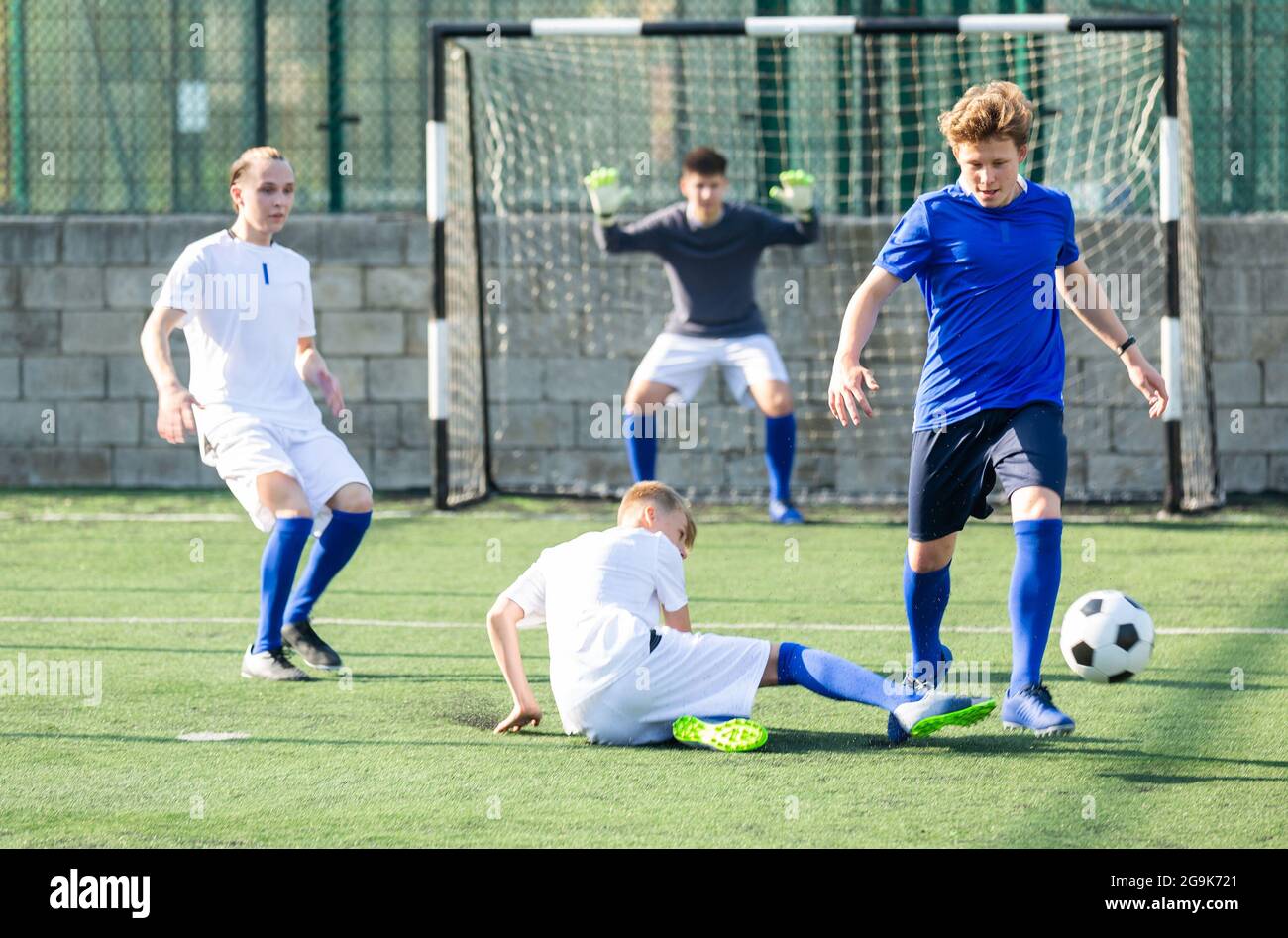 Game of football match between two teams of teenagers in white and blue ...