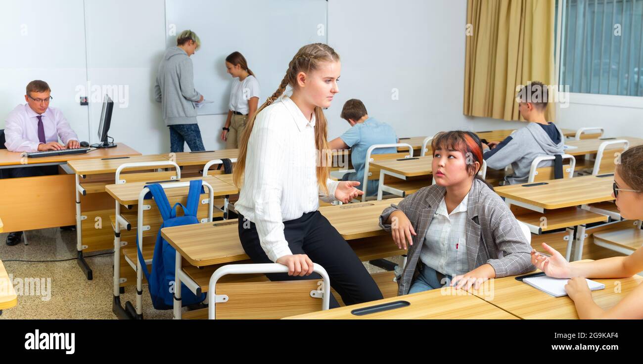 Positive students are talking about homework at desk Stock Photo - Alamy