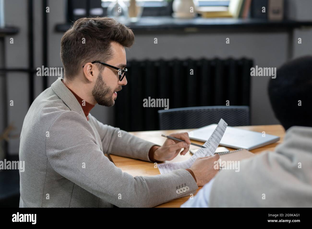 Male speaker or coach pointing at paper while looking through data ...