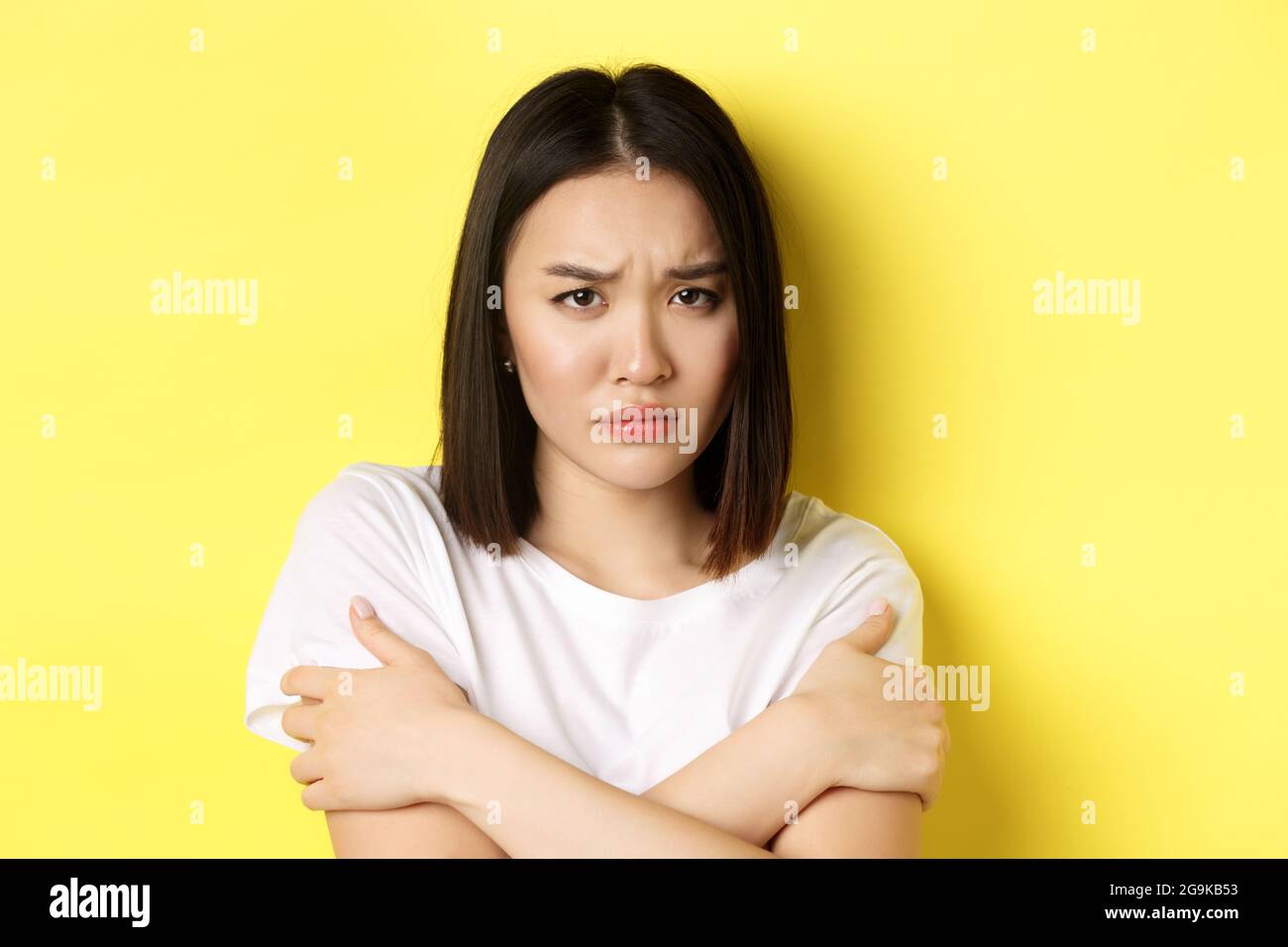 Sad timid girl comforting herself, hugging body and frowning upset ...