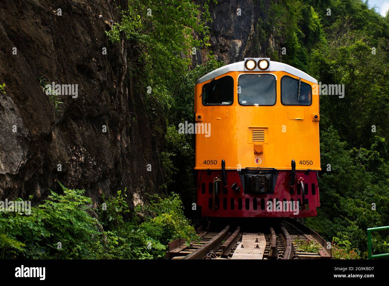 Train running on track between hellfire pass mountain and riverside Sai ...