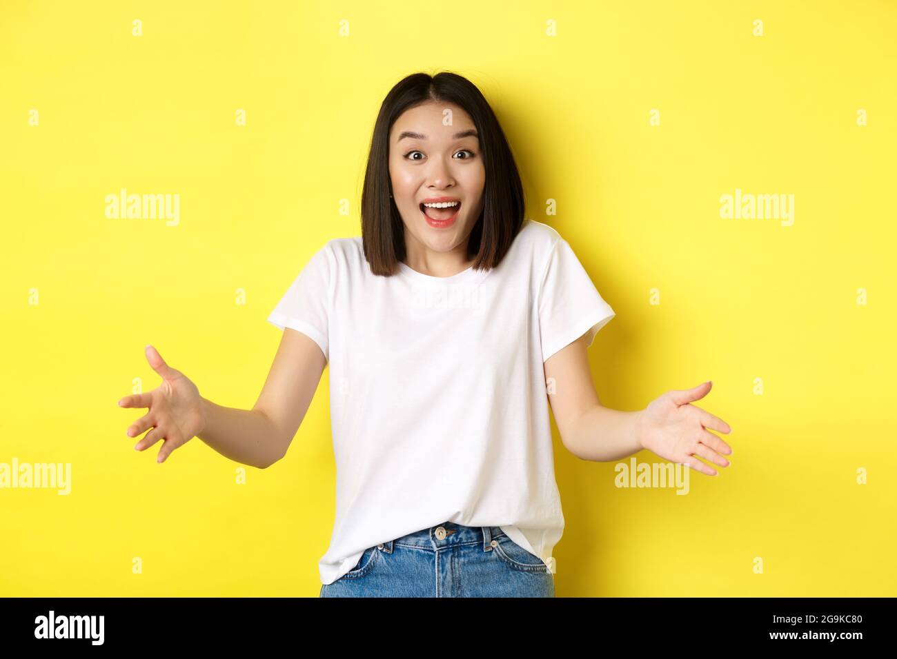 Excited young asian woman spread out hands as if holding large, big ...