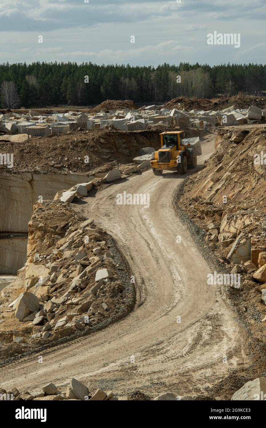 Large tractor moving down road towards building place Stock Photo - Alamy