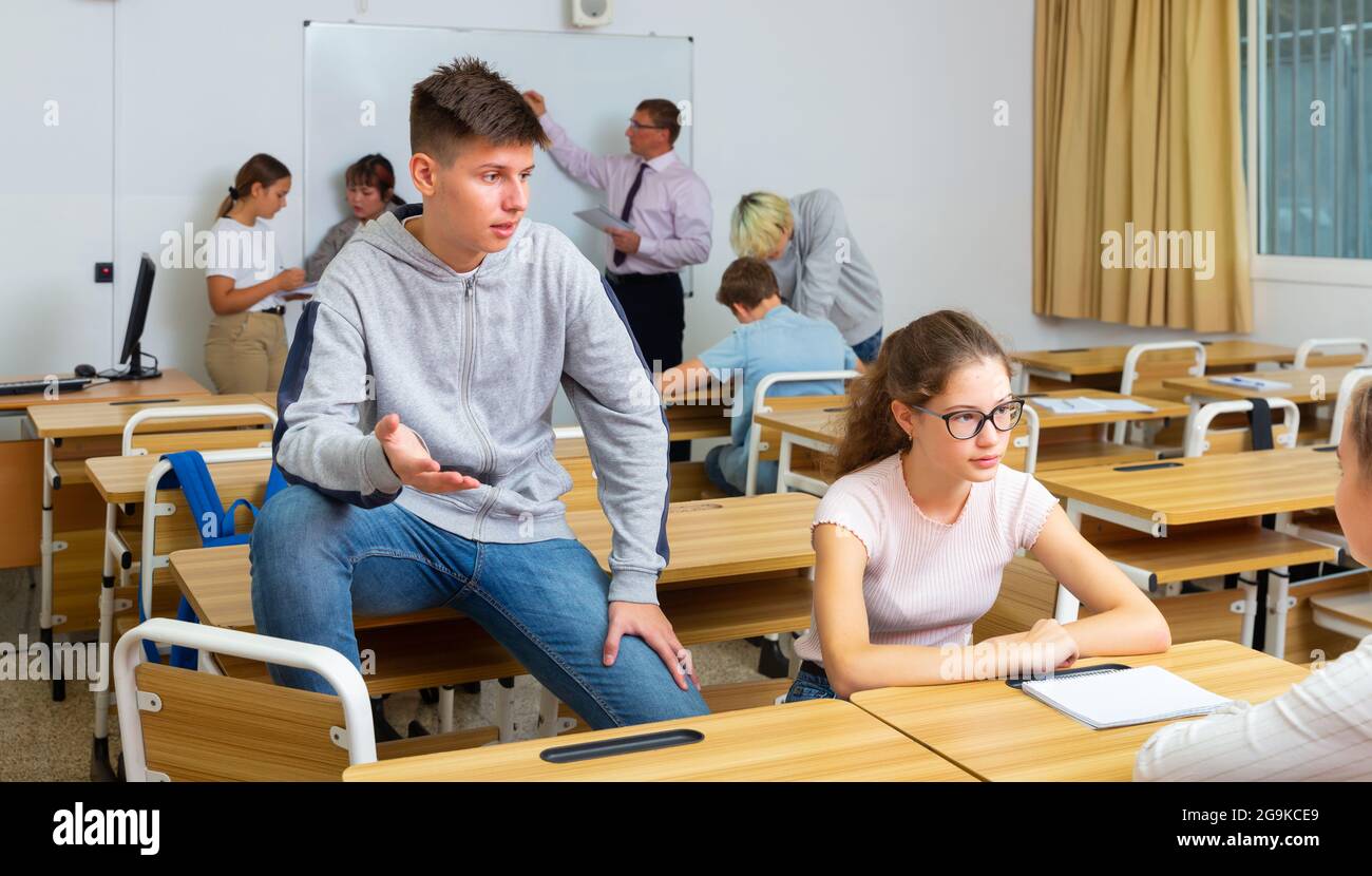 Teen students communicating during recess in classroom Stock Photo - Alamy