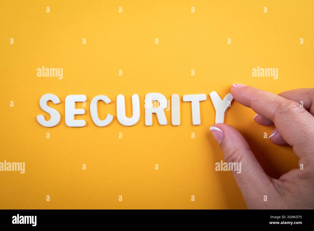 SECURITY. White wooden letters with text and a woman's hand on a yellow ...