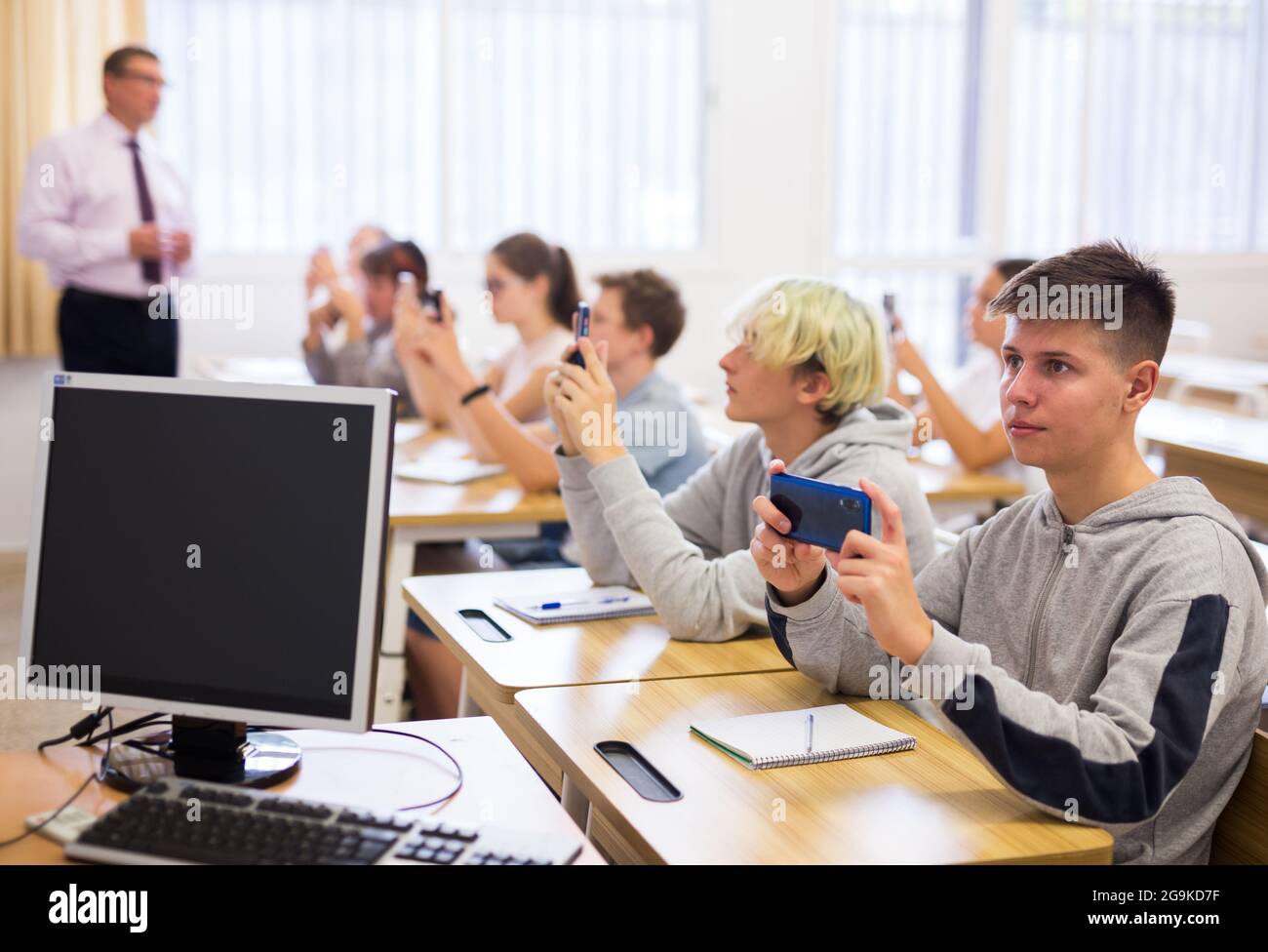 Teen students using social media on phones on lesson Stock Photo - Alamy