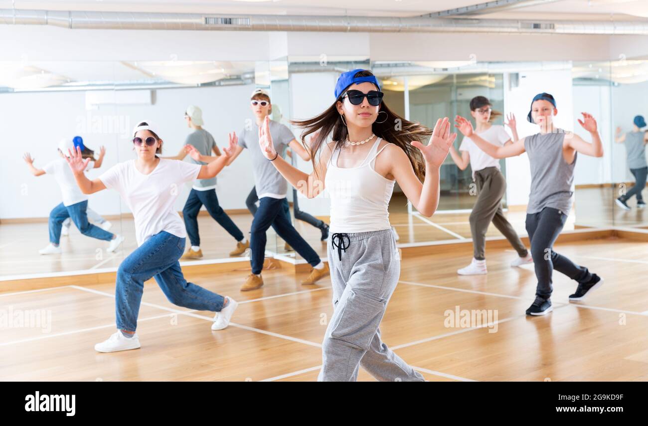 Happy smiling teenagers practicing vigorous hip hop movements in class ...