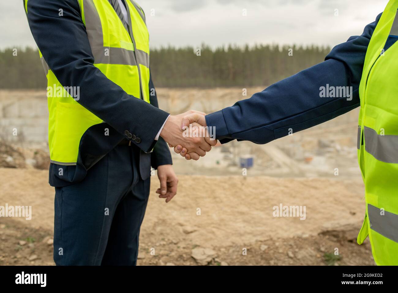 Handshake of contractor and female builder against construction site ...