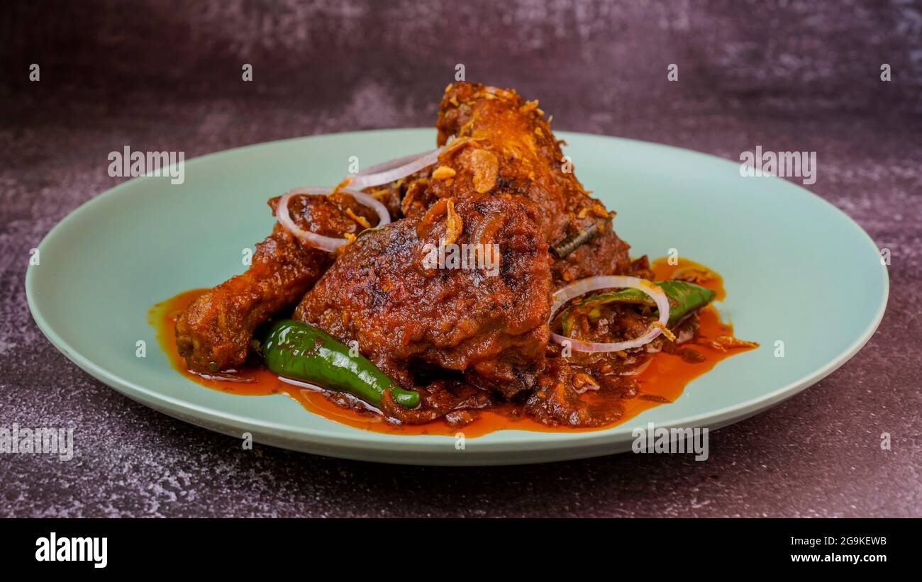 Chicken cooked in dry spicy red curry garnished with onion ring and ...