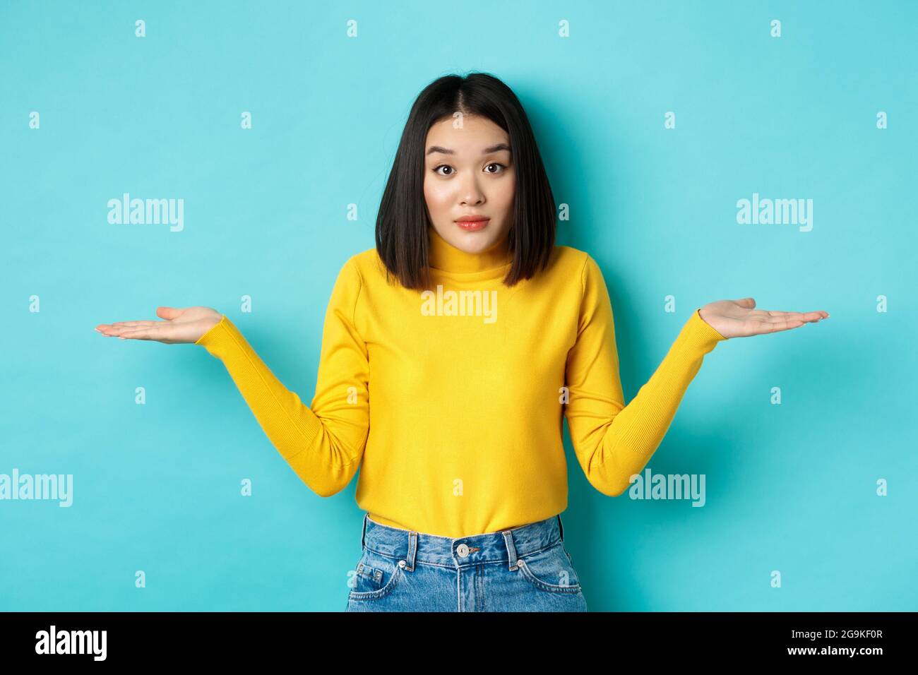 Image of indecisive asian woman shrugging shoulders, spread hands ...