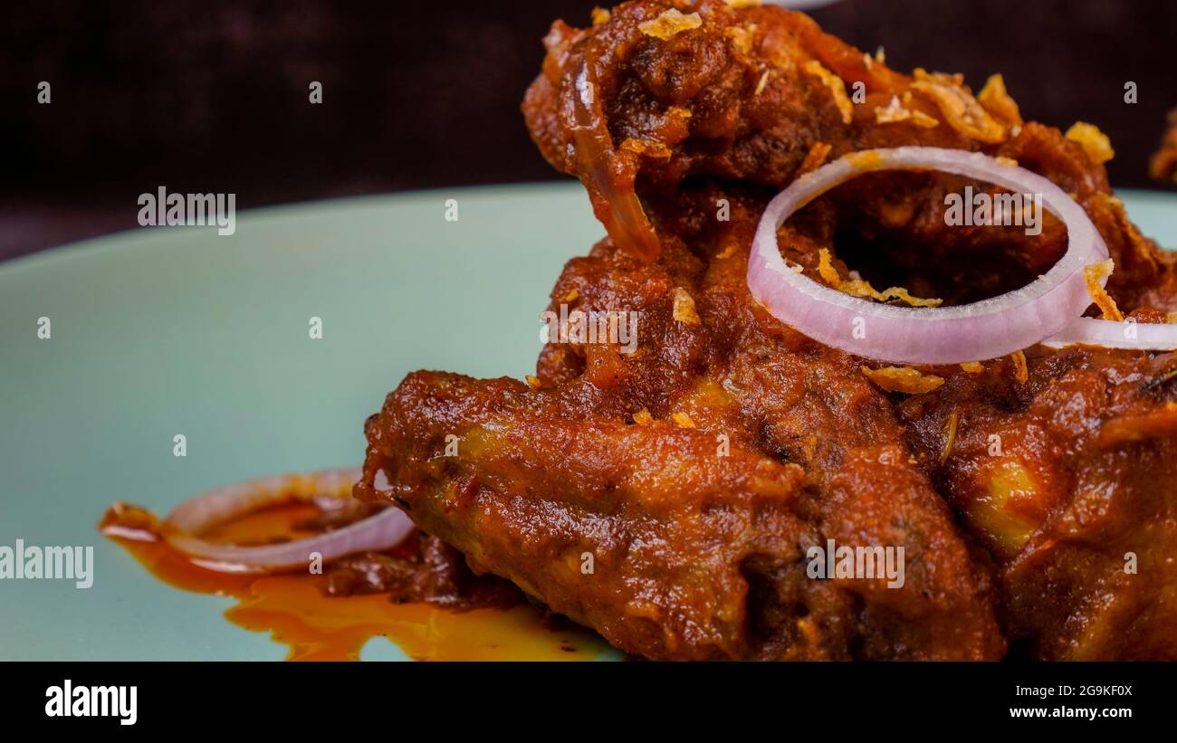 Chicken cooked in dry spicy red curry garnished with onion ring and ...